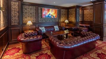 Quarto luxuoso com um amplo sofá de couro, uma mesa de centro de madeira e uma lareira com fogo.