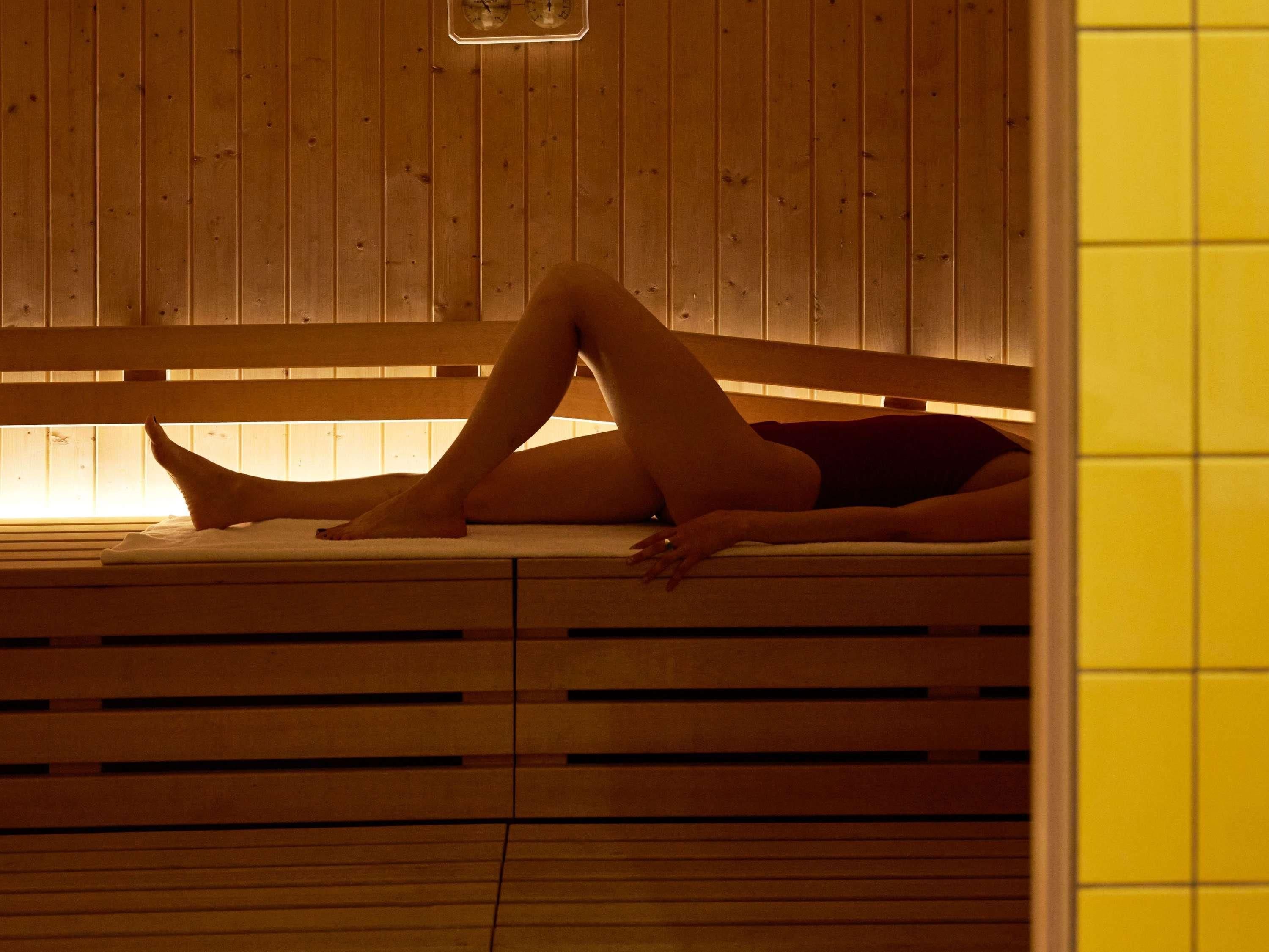 Uma sauna com bancos de madeira e parede revestida de azulejos.