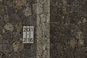 Um muro de pedra com uma placa mostrando os números '201-216'.