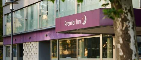 Um edifício com a placa da Premier Inn, exibindo um logotipo com uma lua crescente e estrelas.
