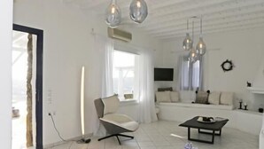 Uma sala de estar moderna com um sofá, uma mesa de centro e luminárias pendentes.