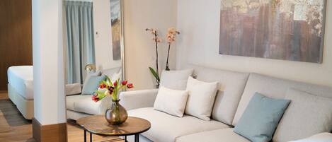Uma sala de estar moderna com um sofá, uma mesa de centro, um vaso com flores, um espelho grande e um quadro na parede.