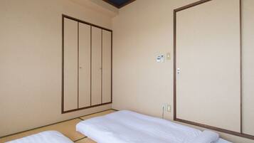 Quarto de hotel com duas camas, um guarda-roupa espaçoso e teto com vigas de madeira.