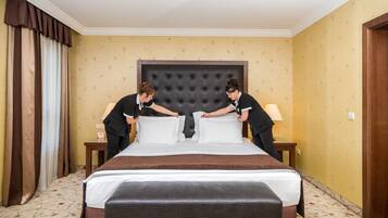 Quarto de hotel com uma cama grande, duas mesas de cabeceira, uma cabeceira e uma janela com cortinas.