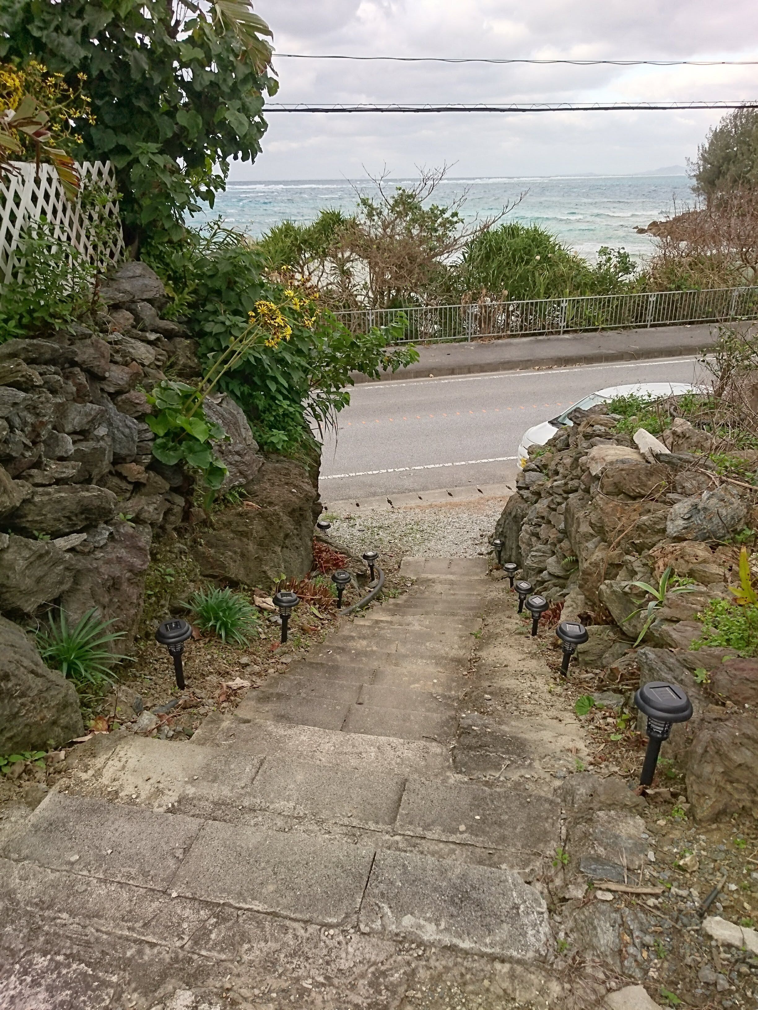 Uma escadaria de pedra leva a uma estrada com vista para o oceano.