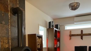 Uma sala de estar moderna com uma lareira a lenha, uma área de jantar com mesa e cadeiras, e uma estante embutida.