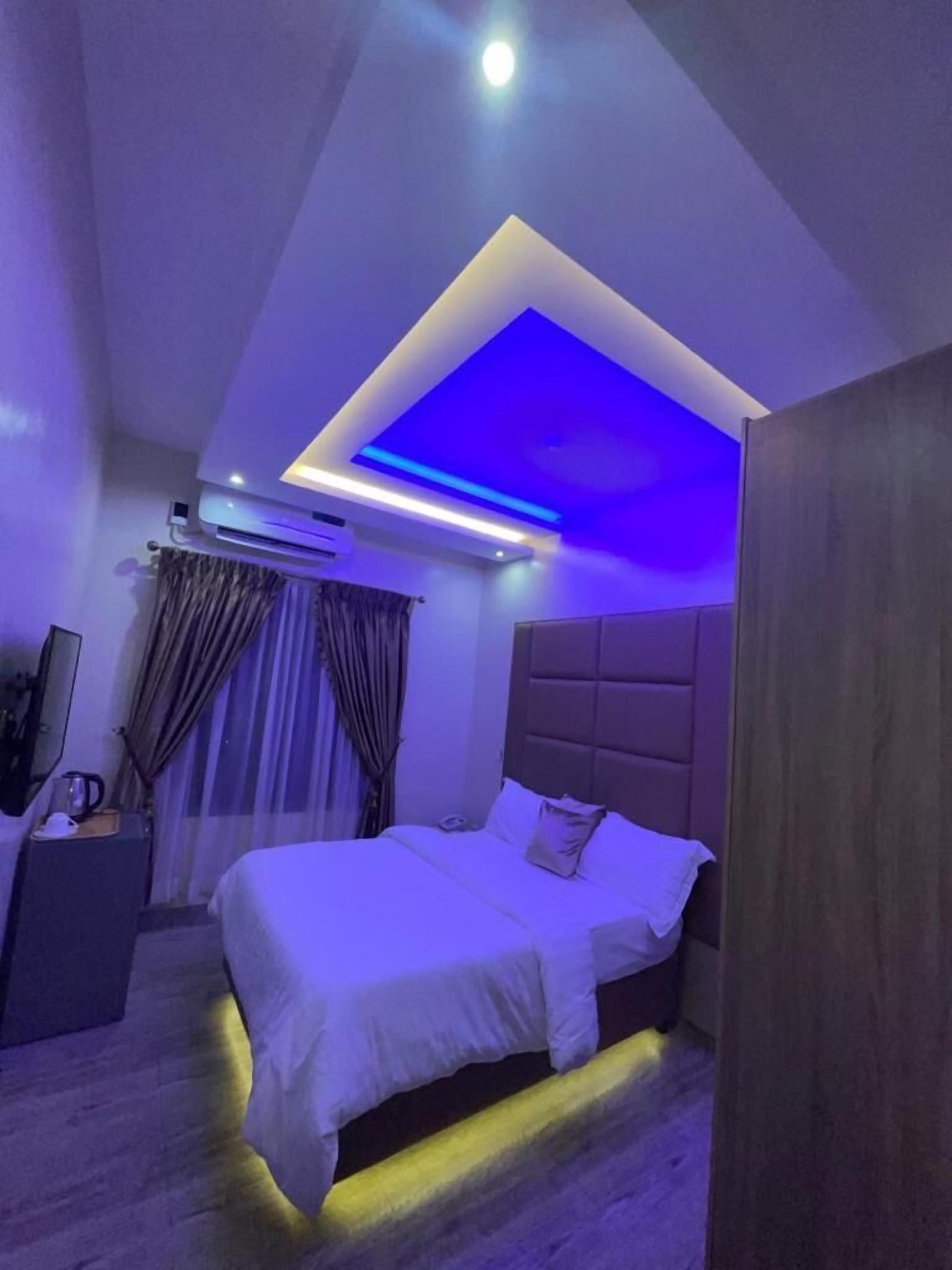 Um quarto moderno com cama, ar condicionado e luminária no teto.