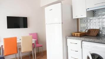 Uma cozinha compacta com geladeira branca, máquina de lavar e painel de azulejos.