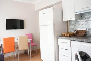 Uma cozinha compacta com geladeira branca, máquina de lavar e painel de azulejos.