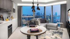 Quarto de hotel moderno com área de jantar, sofá e televisão.