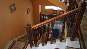 Uma escadaria de madeira com corrimão, degraus carpetados e parede estampada.