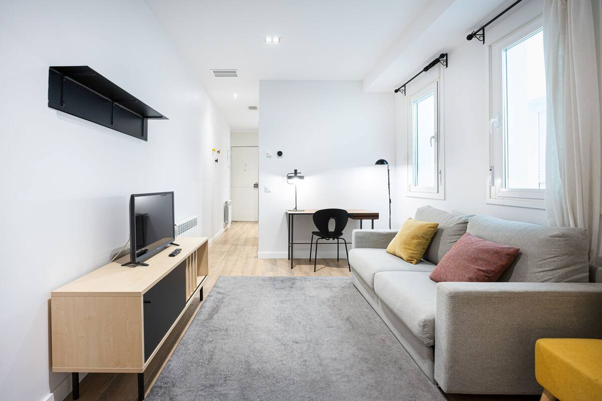 Uma sala de estar moderna com televisão, sofá e escrivaninha.