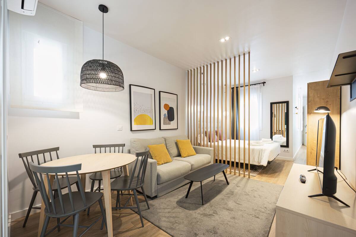 Uma sala de estar moderna com área de jantar, sofá, mesa de centro e televisão em um móvel.