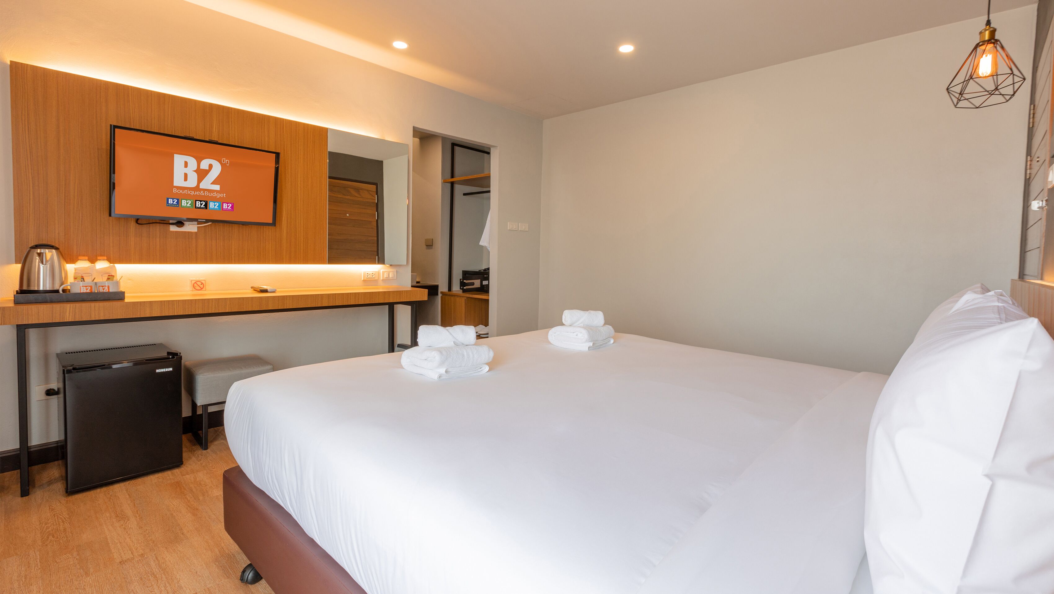 Quarto de hotel com cama, escrivaninha, televisão, cafeteira e minibar.
