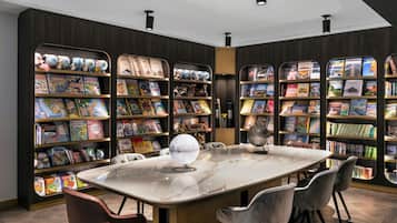 Uma biblioteca moderna com uma grande mesa de mármore, várias estantes e assentos confortáveis.