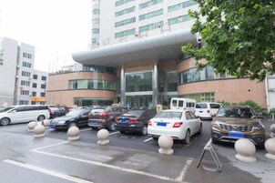 Um estacionamento com vários carros e um edifício de fachada curva.
