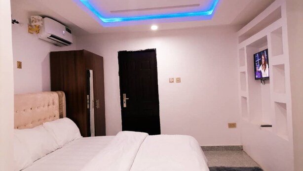 Quarto com cama, guarda-roupa e televisão na parede.