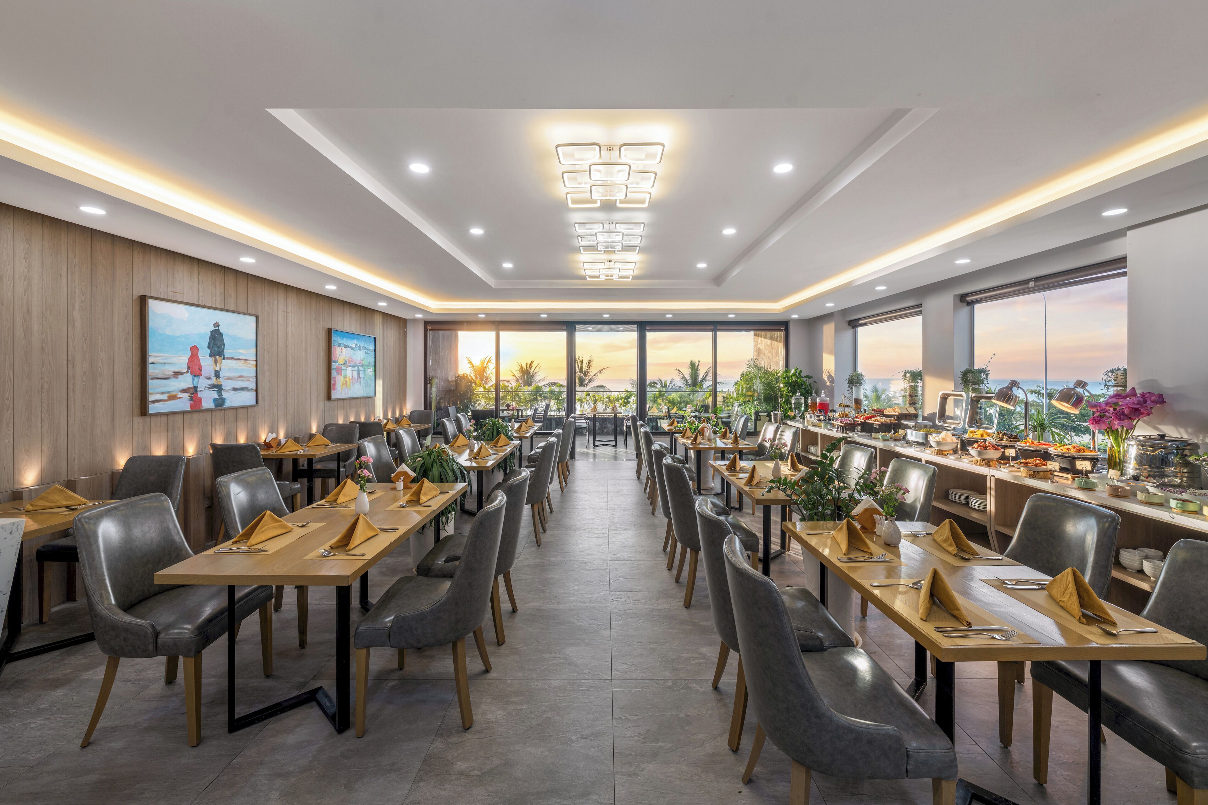 Uma área de refeições moderna com mesas longas, cadeiras e um buffet.