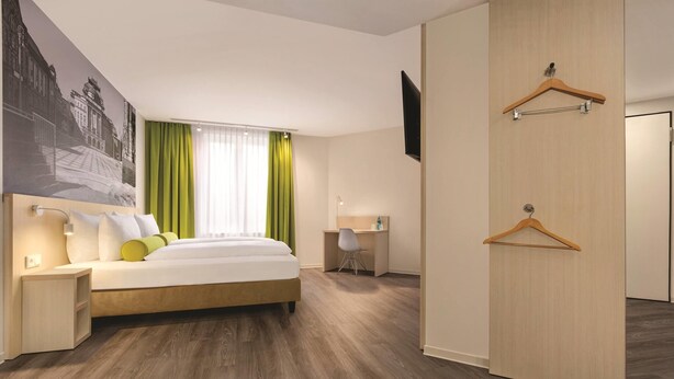 Quarto de hotel moderno com uma cama grande, uma escrivaninha e um guarda-roupa.
