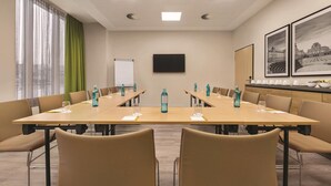 Uma sala de conferência com uma mesa comprida, cadeiras, um quadro branco e quadros nas paredes.
