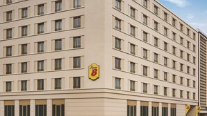 Edifício de hotel com vários andares, fachada uniforme, grandes janelas e um logotipo destacado no canto.