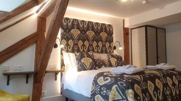 Um quarto com cama, mesa de cabeceira, abajur e guarda-roupa.
