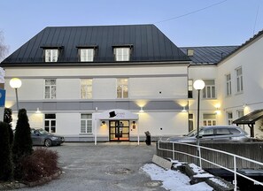 Um hotel com telhado escuro, várias janelas e uma placa com a inscrição "Henriks Hotel".