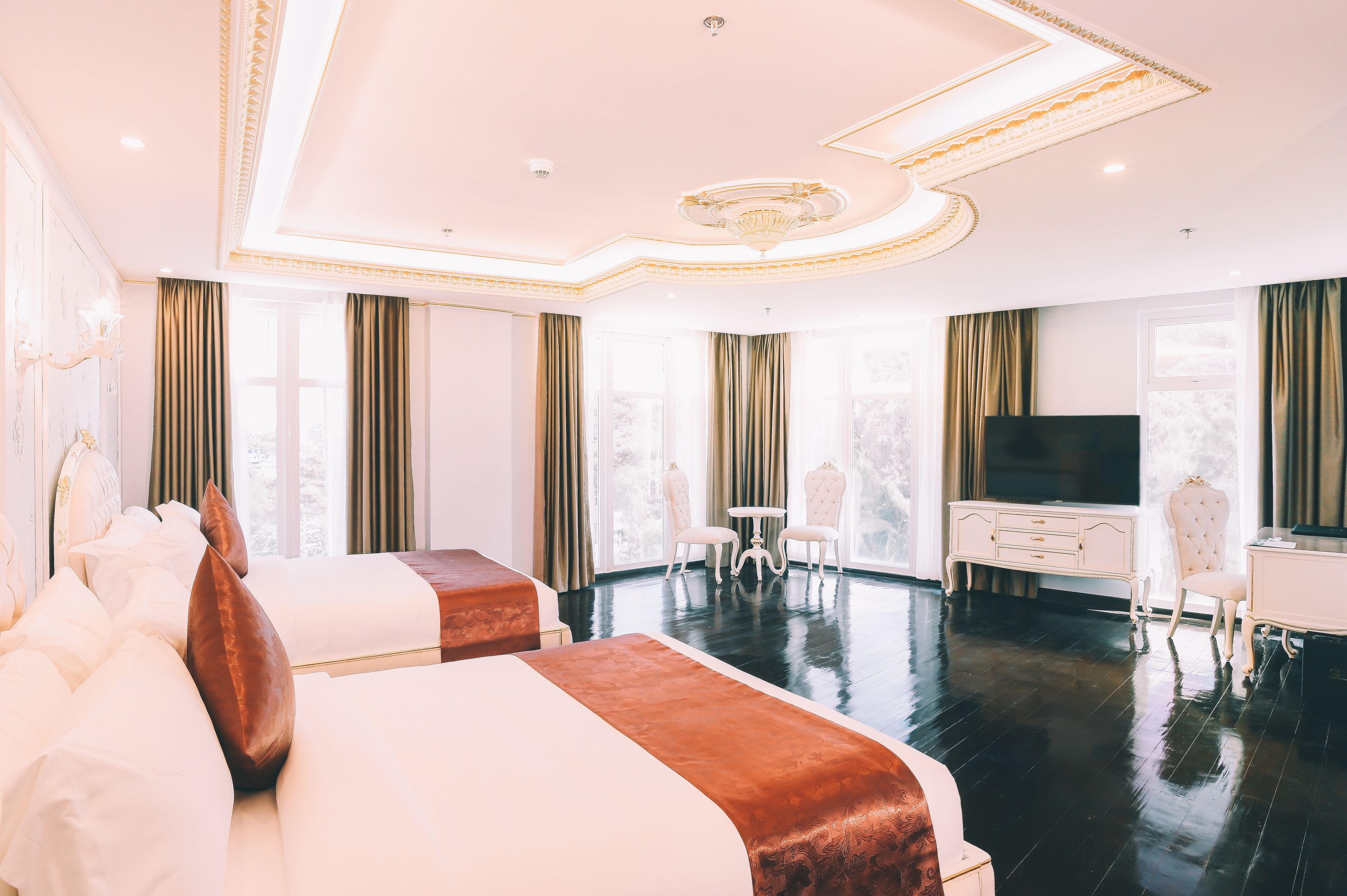 Quarto de hotel espaçoso com uma cama grande, uma televisão, uma escrivaninha e uma cadeira.