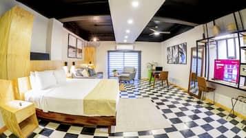 Quarto de hotel moderno com piso quadriculado, uma cama grande, uma escrivaninha e uma televisão.