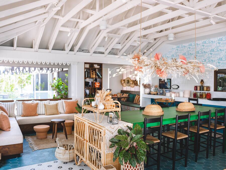 Uma sala de estar ampla com pé direito alto, uma mesa de jantar verde e um espaço de bar.