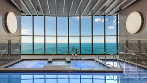 Piscina interna com vista para o oceano, janelas amplas e design moderno.