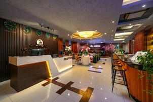 Uma área de recepção de hotel com balcão, café e assentos.