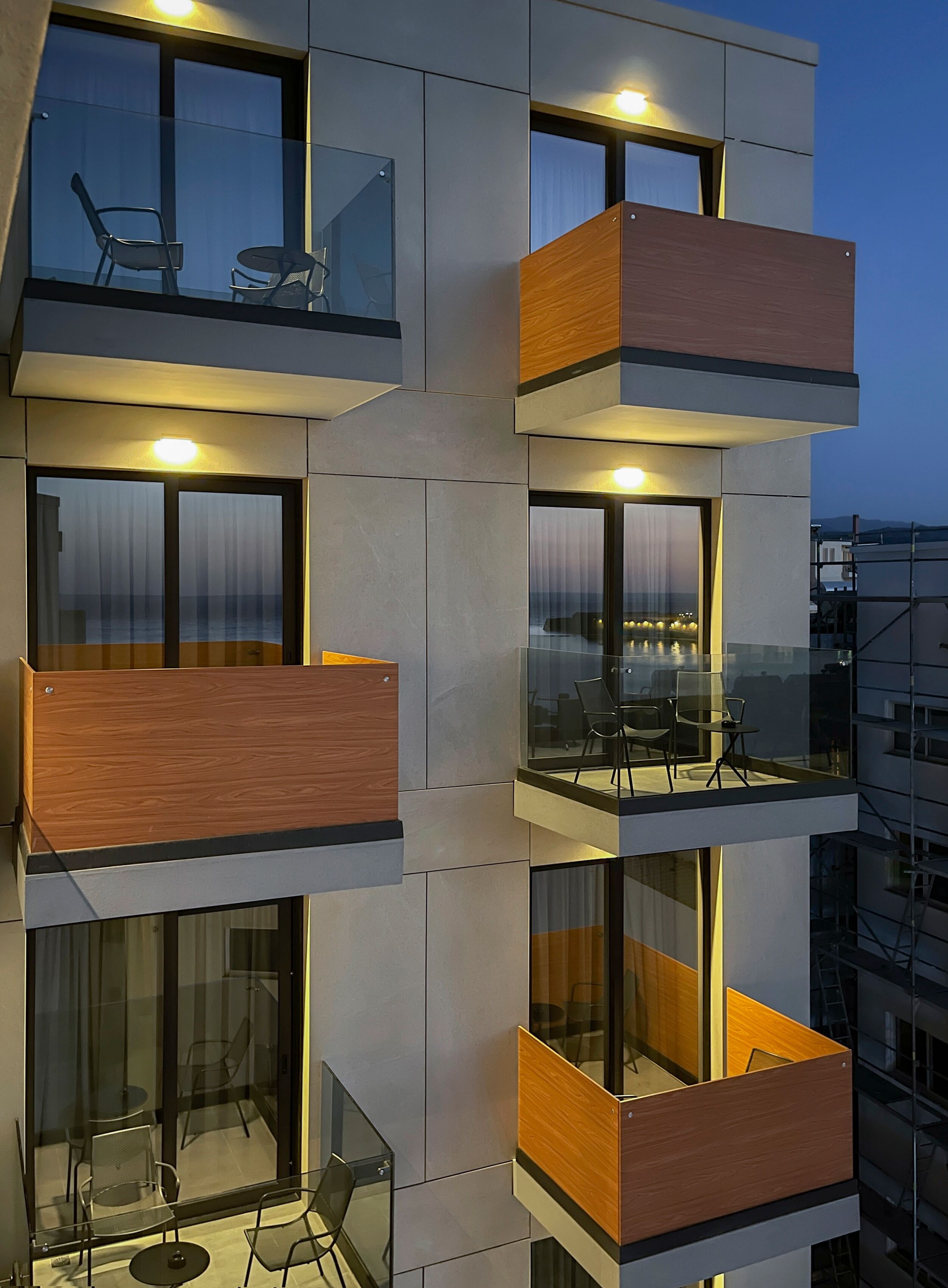 Um edifício moderno de vários andares, com varandas, janelas amplas e vista para a paisagem urbana.