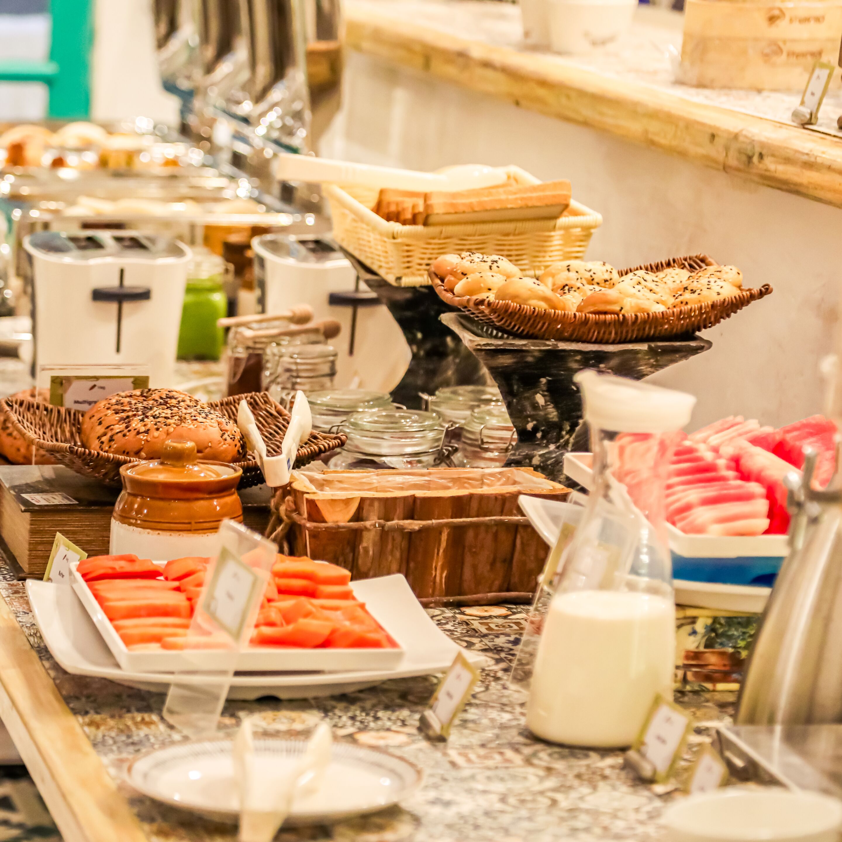 Buffet com diversos alimentos, incluindo pães, doces e frutas.