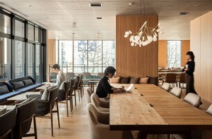 Uma sala de conferências moderna com uma longa mesa de madeira, assentos confortáveis e grandes janelas com vista para o exterior.