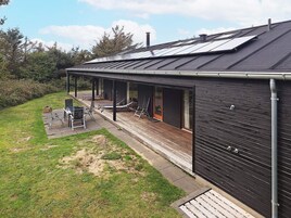 Uma casa moderna com varanda coberta, área de estar externa e uma grande janela.