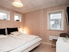 Quarto com cama, escrivaninha e janela com persianas.