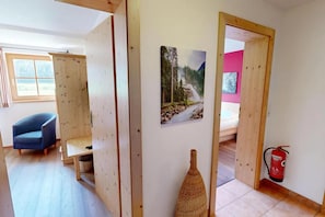 Quarto com cama, cadeira, quadro e extintor de incêndio.