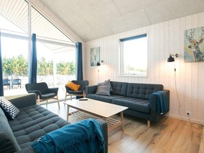 Uma sala de estar moderna com sofá, poltronas, mesa de centro e um quadro na parede.