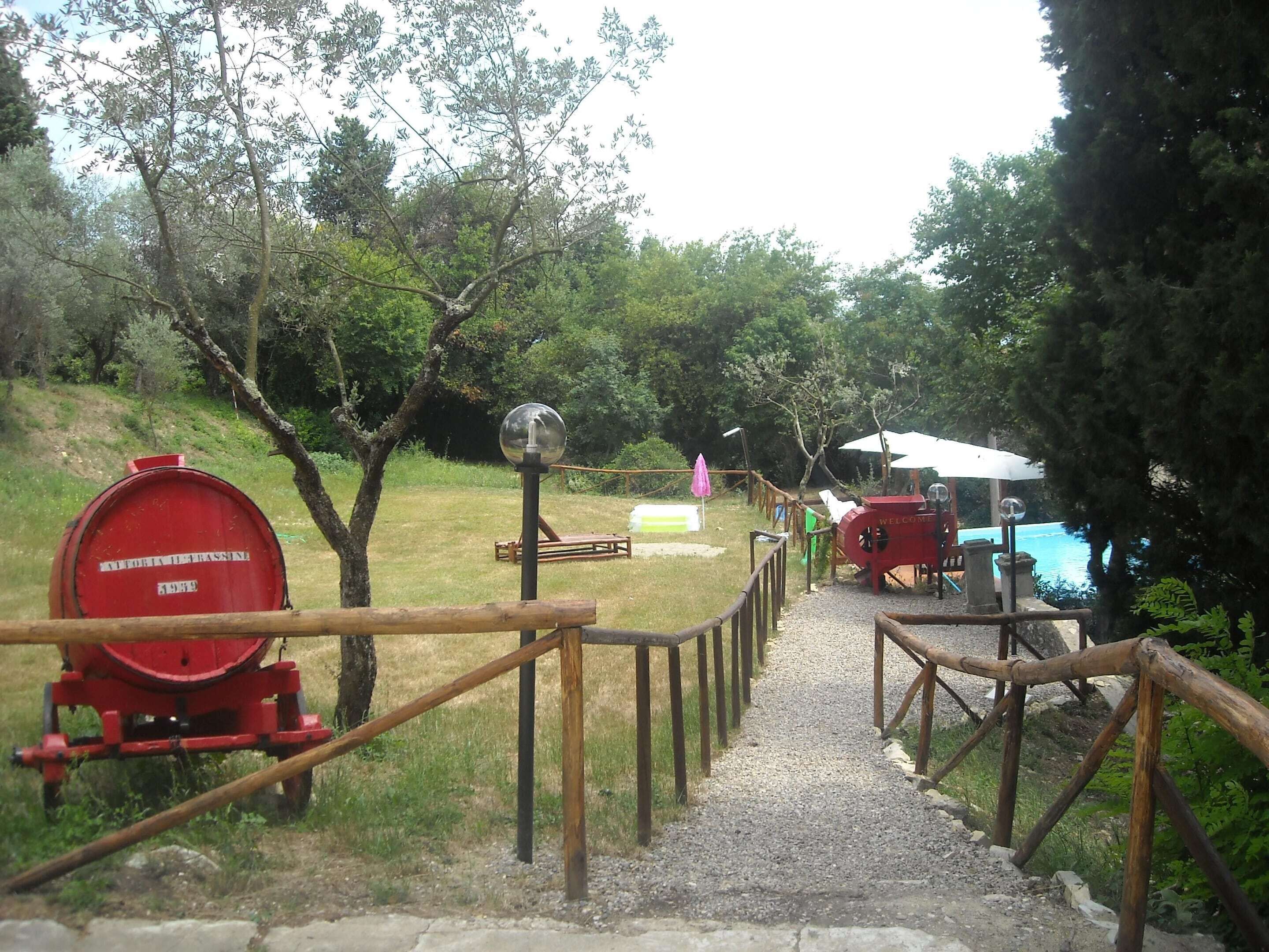 Uma trilha leva a um barril vermelho com a inscrição "A FORZA L'URBANO" e uma área de recreação com uma placa de "WELCOME".