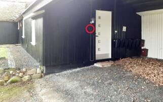 Um edifício com porta de garagem, porta de entrada e um pequeno espaço ao ar livre com cascalho e algumas pedras.