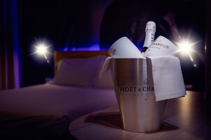 Uma taça metálica com uma garrafa de champanhe Moët & Chandon e um guardanapo sobre um tabuleiro de madeira.
