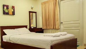 Cama bem arrumada com lençóis brancos, cabeceira de madeira, mesa de cabeceira com abajur e um quadro na parede.