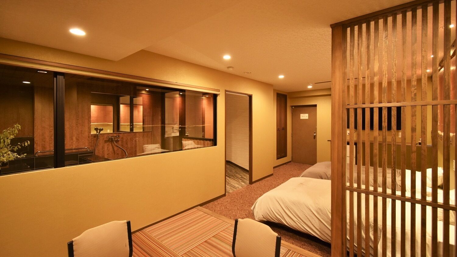Quarto de hotel com um espelho grande, uma cama, uma cadeira e um divisória de madeira.