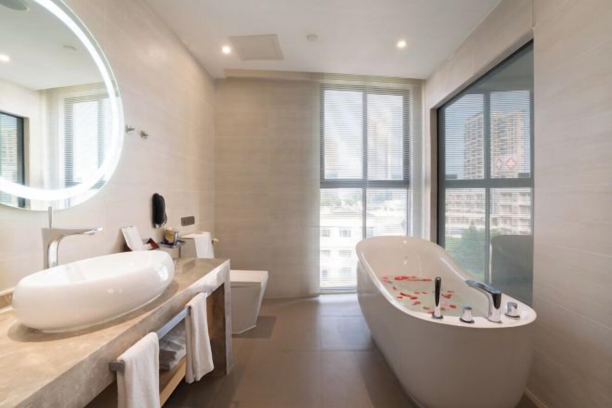 Uma casa de banho moderna com uma banheira grande, um espelho redondo e um lavatório duplo.