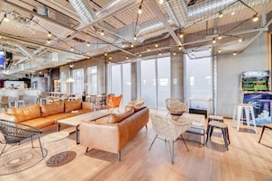 Uma área de estar moderna com sofás de couro, cadeiras de metal e um bar com banquetas.