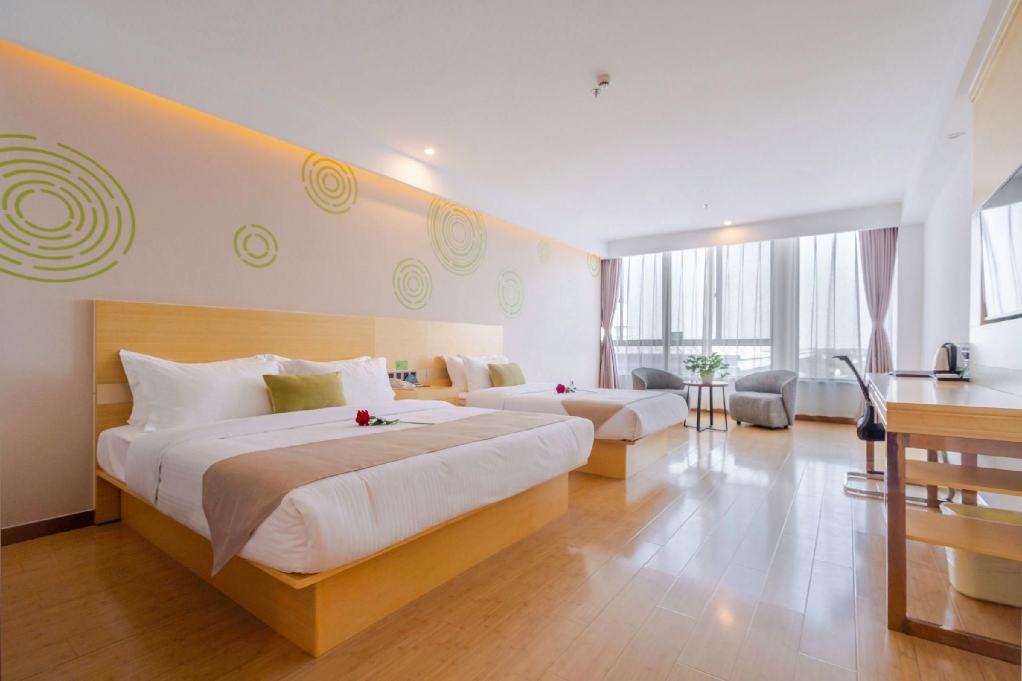 Quarto de hotel moderno com uma cama grande, uma cama menor, uma escrivaninha e uma cadeira.