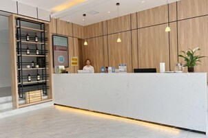 Bancada de recepção com design moderno, painel de parede em madeira e iluminação pendente.