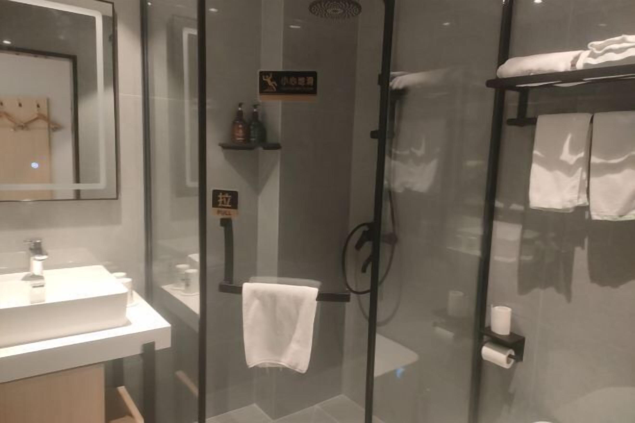 Uma casa de banho moderna com chuveiro de vidro, pia branca e porta-toalhas.