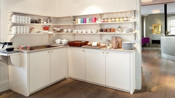 Uma cozinha moderna com armários brancos, uma ilha integrada e diversos utensílios e eletrodomésticos.